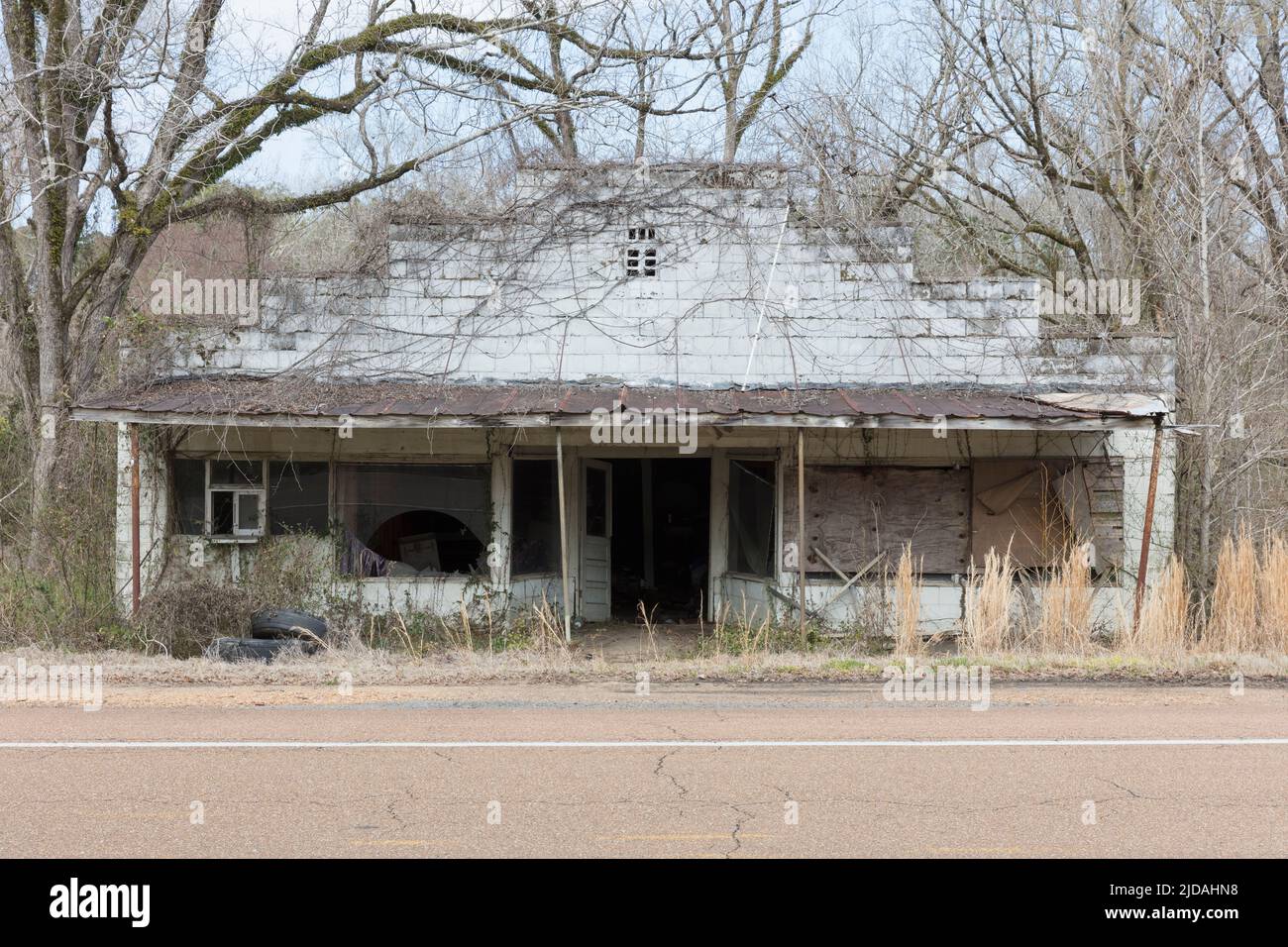 A rural homestead or small house abandoned and crumbling, overgrown ...