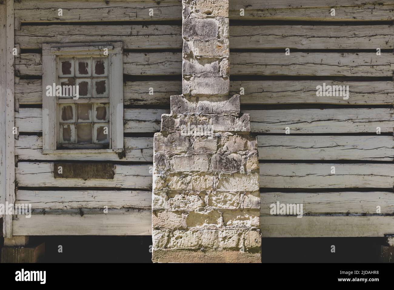 An abandoned log cabin with a stone chimney flue, cracked and dried out ...