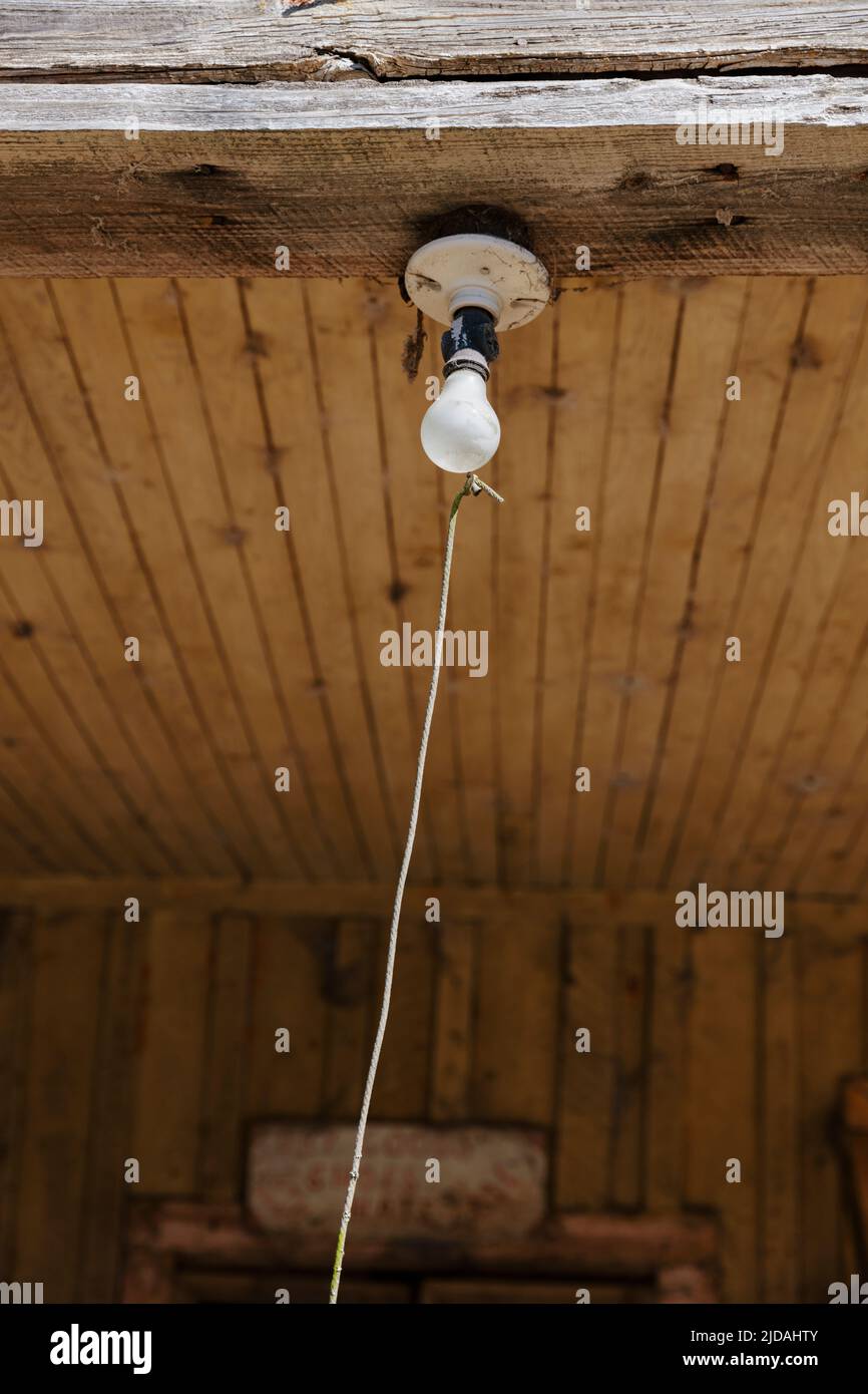 Old incandescent light bulb on a porch beam with a string pull control ...