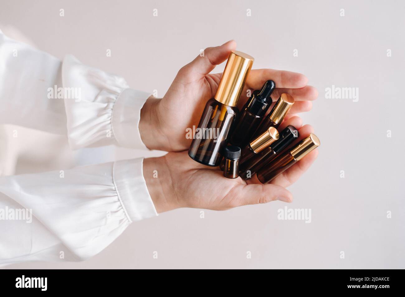 Close-up of female hands holding many bottles of essential oil ...