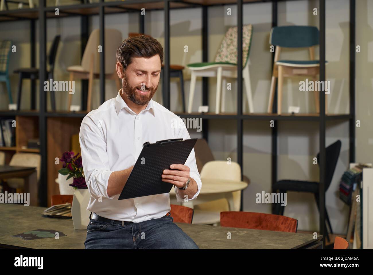 Front view of handsome brunette male with beard designing in furniture ...