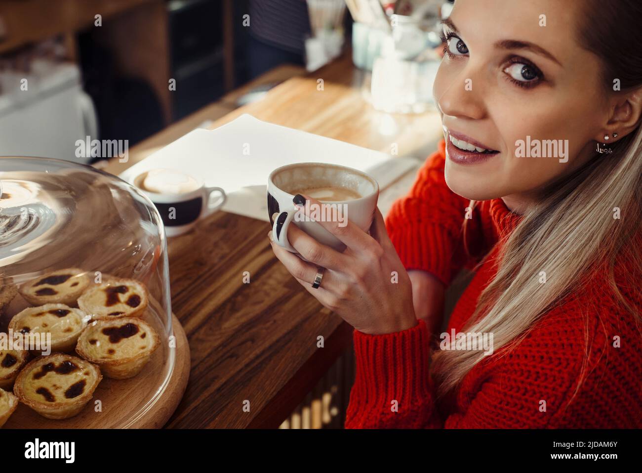 Pretty young women drinking hot coffee in cafe. Person holding cup of ...