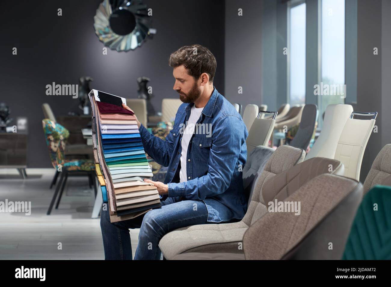 Side view of young brunette male thinking, choosing fabric in furniture ...