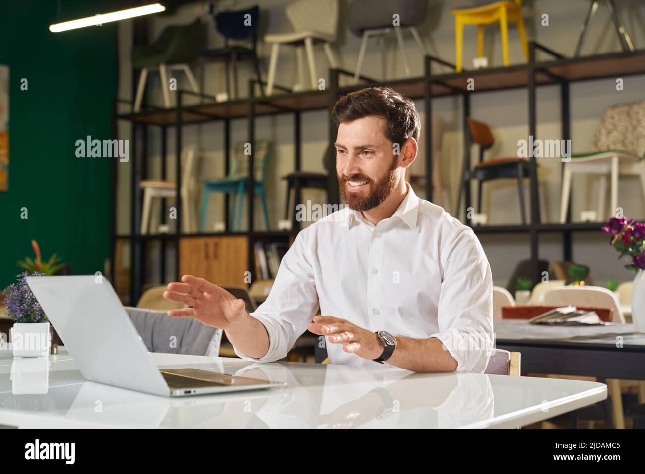 Front view of happy designer, architect sitting at table, working ...