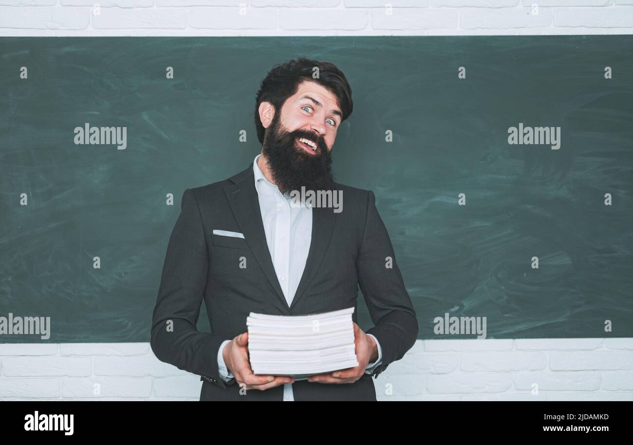 Friendly teacher in classroom near blackboard desk. Teachers challenges ...