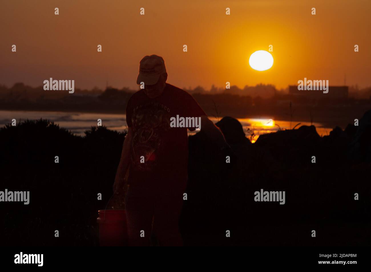 fisherman coming back home with a pail full of fishes at sunset Stock ...
