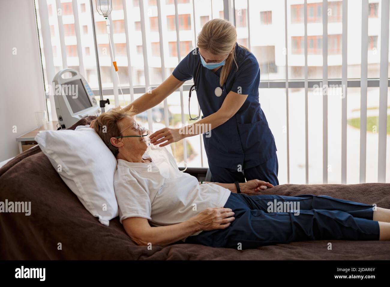 Doctor putting on a breathing mask on a female patient with covid-19 in ...