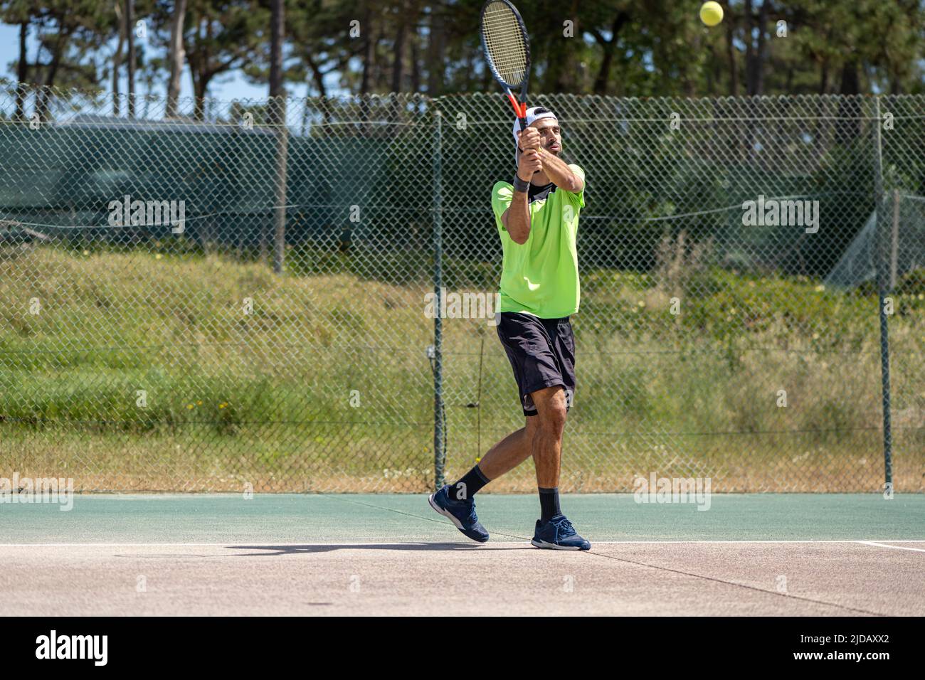 Tennis player hitting backhand at ball with racket on court Stock Photo ...