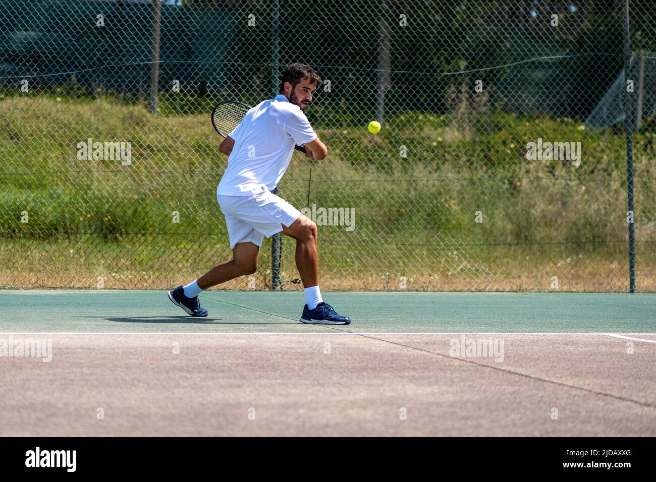 Tennis player hitting backhand at ball with racket on court Stock Photo ...