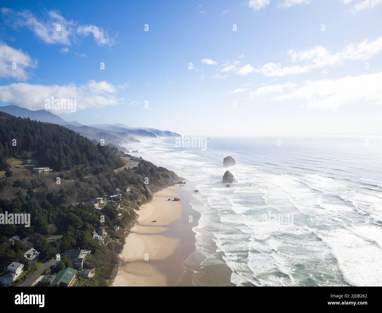A small town on a hilly green shore of the ocean. Sandy beach, light ...
