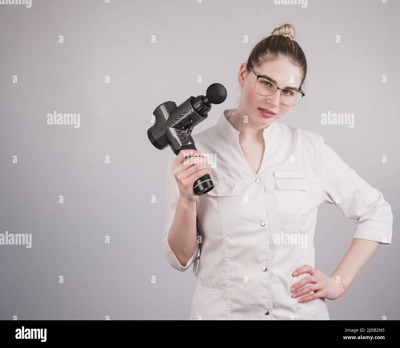 The masseur doctor holds a masseur gun on a white background Stock ...