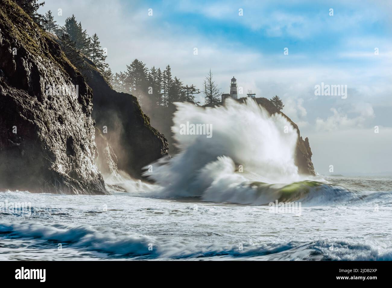 Cape Disappointment Light with large waves crashing in onto the beach ...