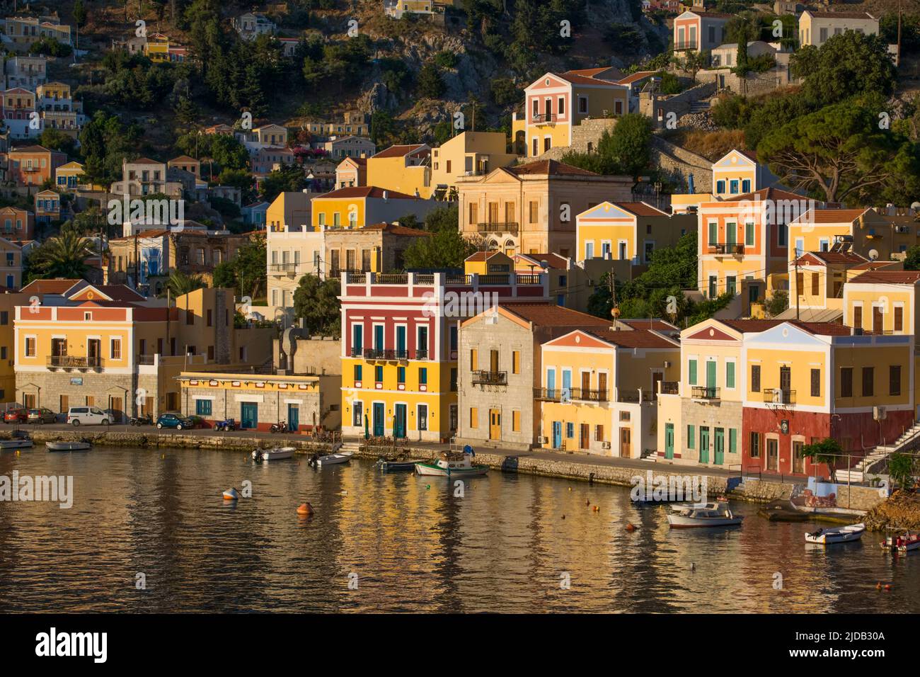 Warm sunlight on the colorful buildings along the waterfront in Gialos ...