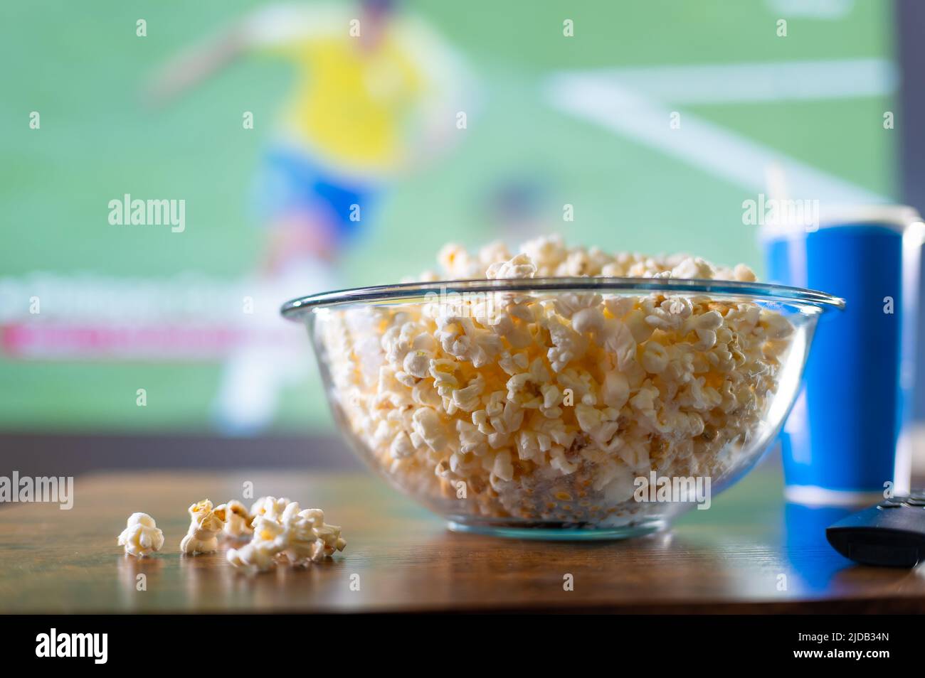 Large glass bowl with popcorn on a sports background. Football match on ...