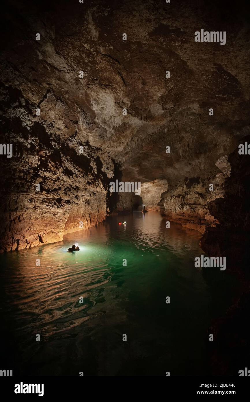 Exploration team members swim in an underground river as they explore ...