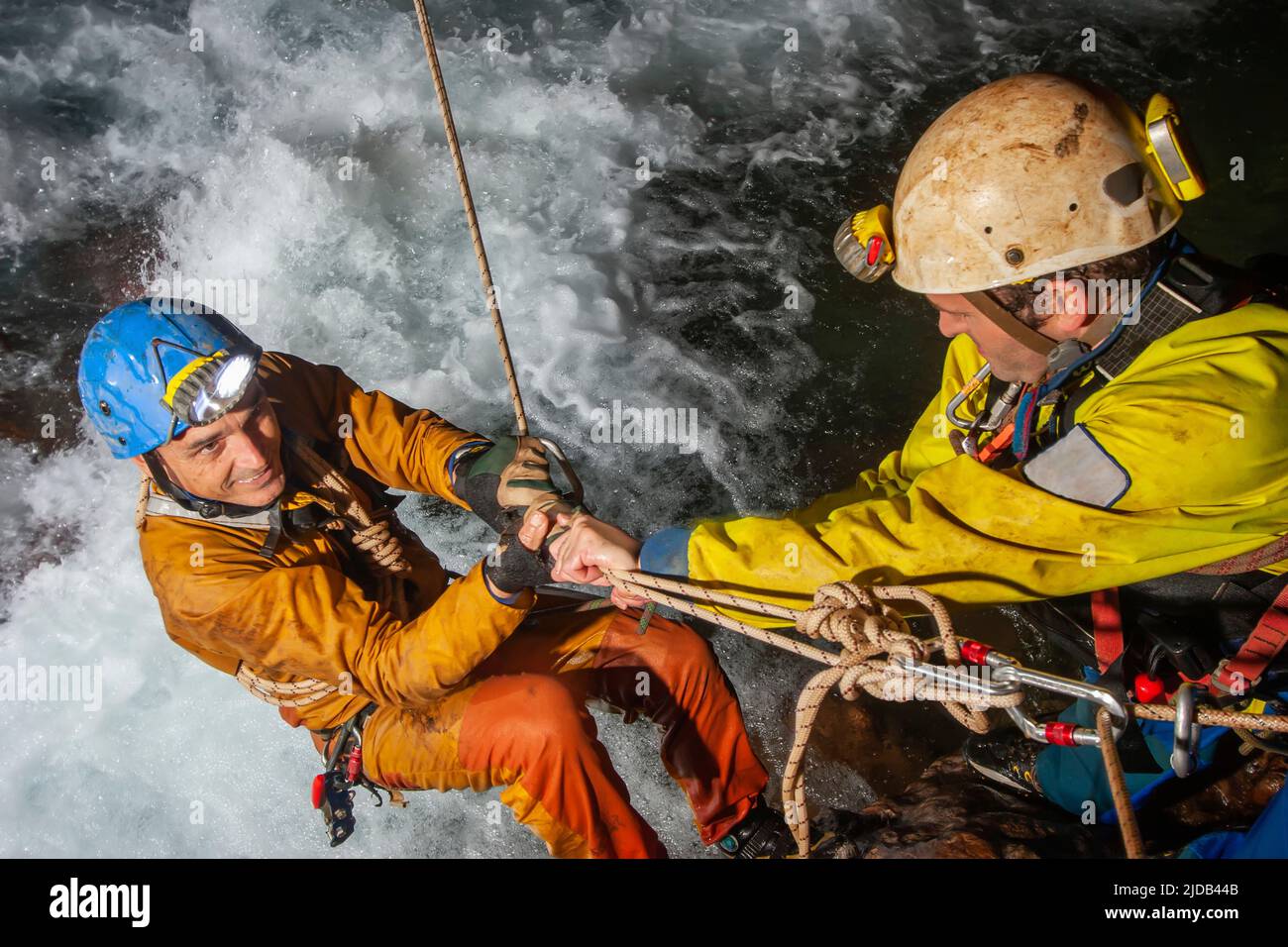 Exploration team members climbing against the rushing river in the Ora ...