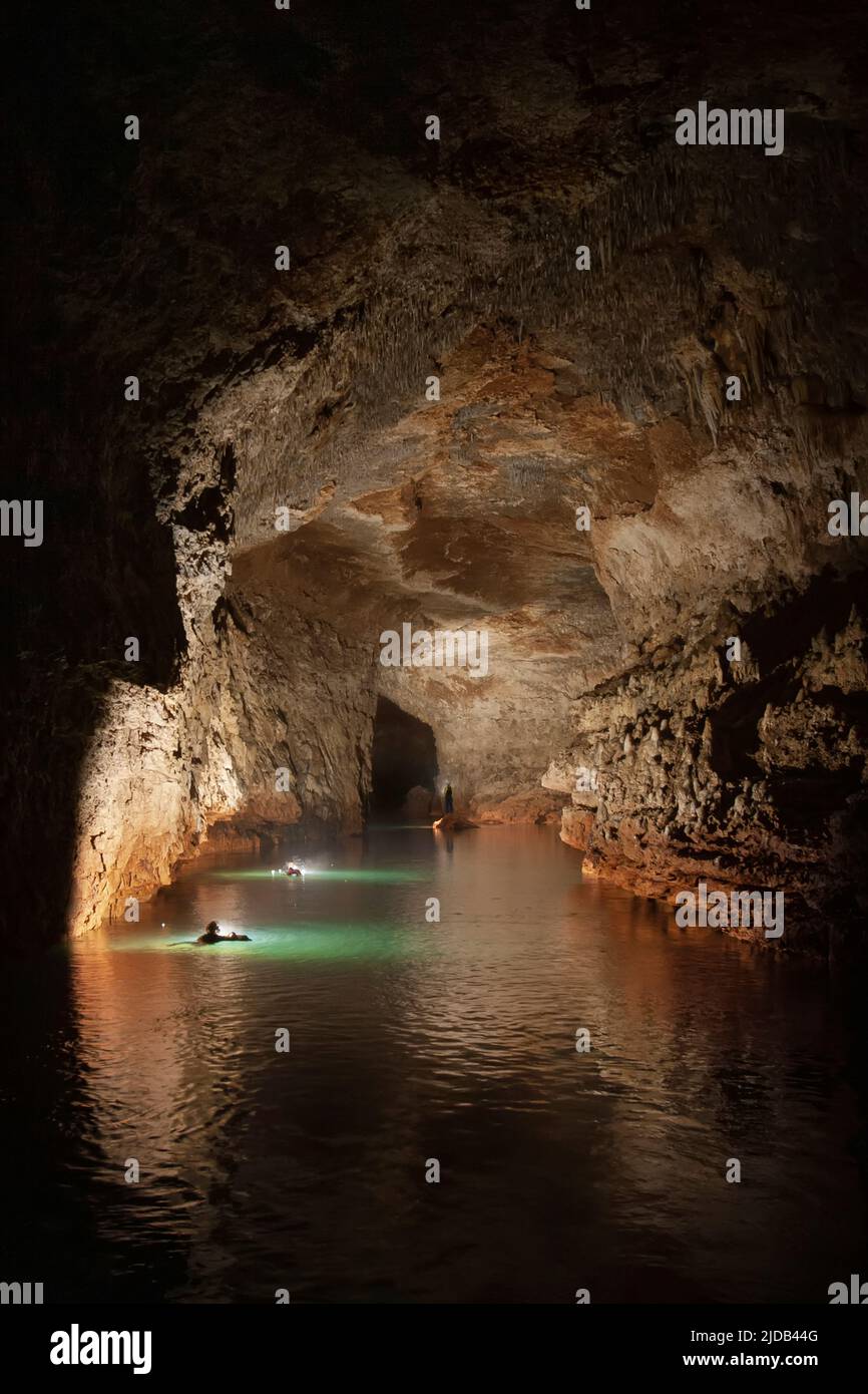 Exploration team members swim in an underground river as they explore ...