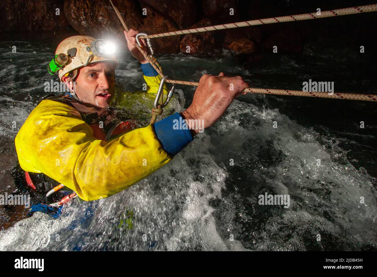 Exploration team member climbing against the rushing river in the Ora ...