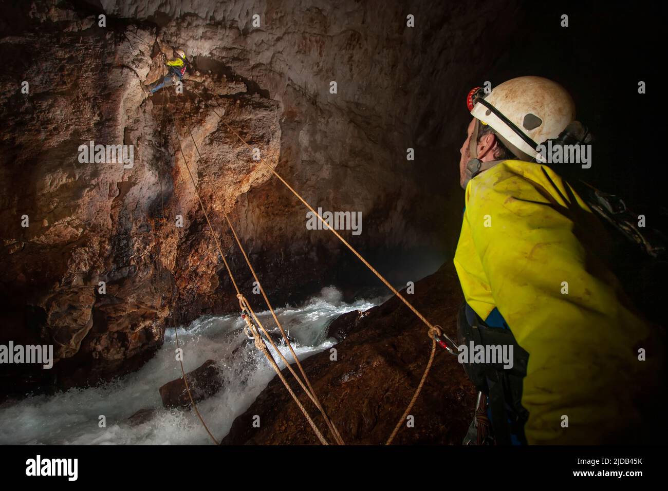 Exploration team members climbing against the rushing river in the Ora ...