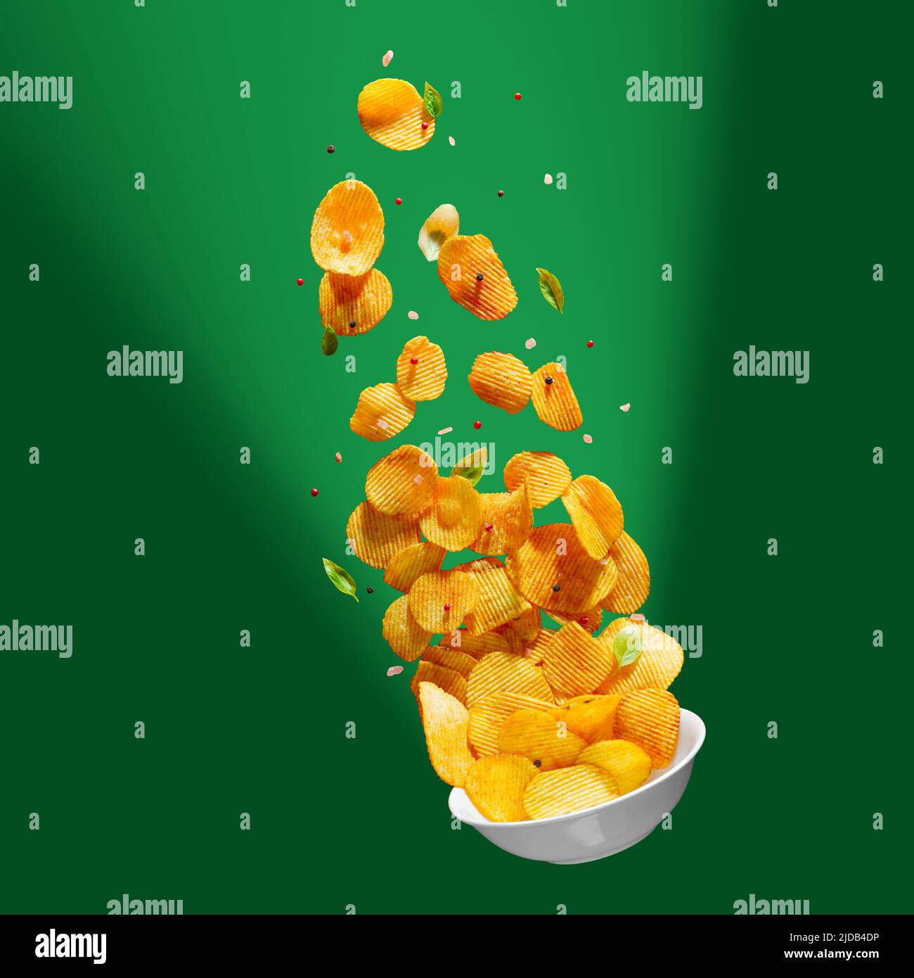 Potato chips falling onto plate on white background. Advertising ...