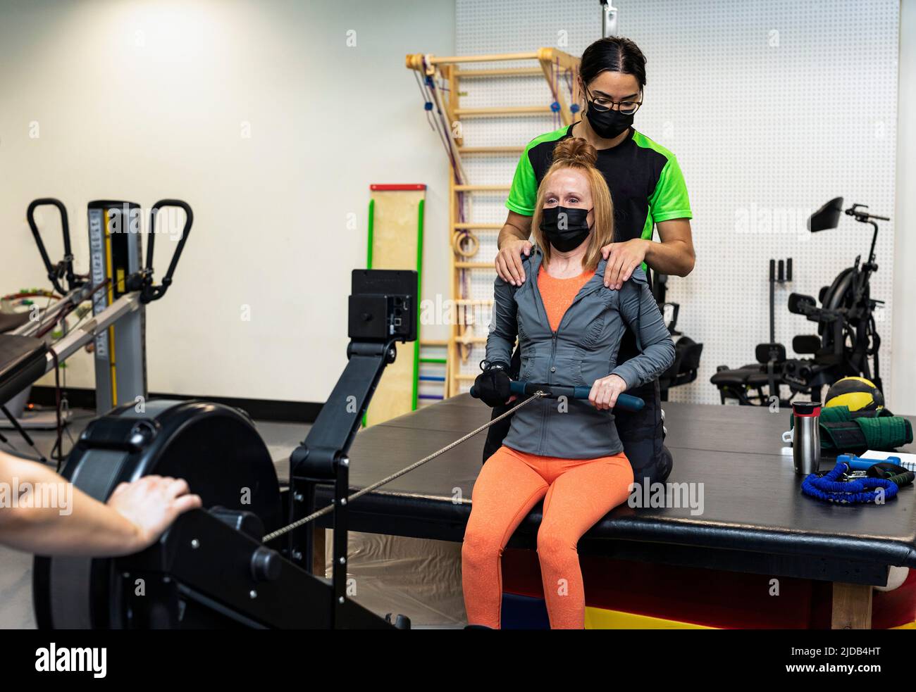 A paraplegic woman working out on a rowing machine with her trainers ...