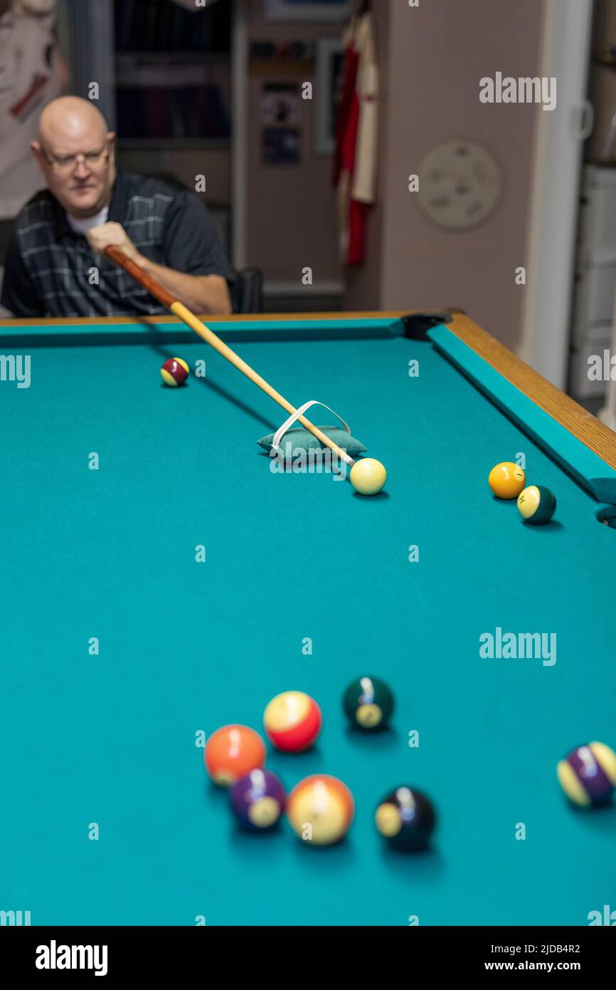 Man with double limb amputations playing a game of pool at home; St ...