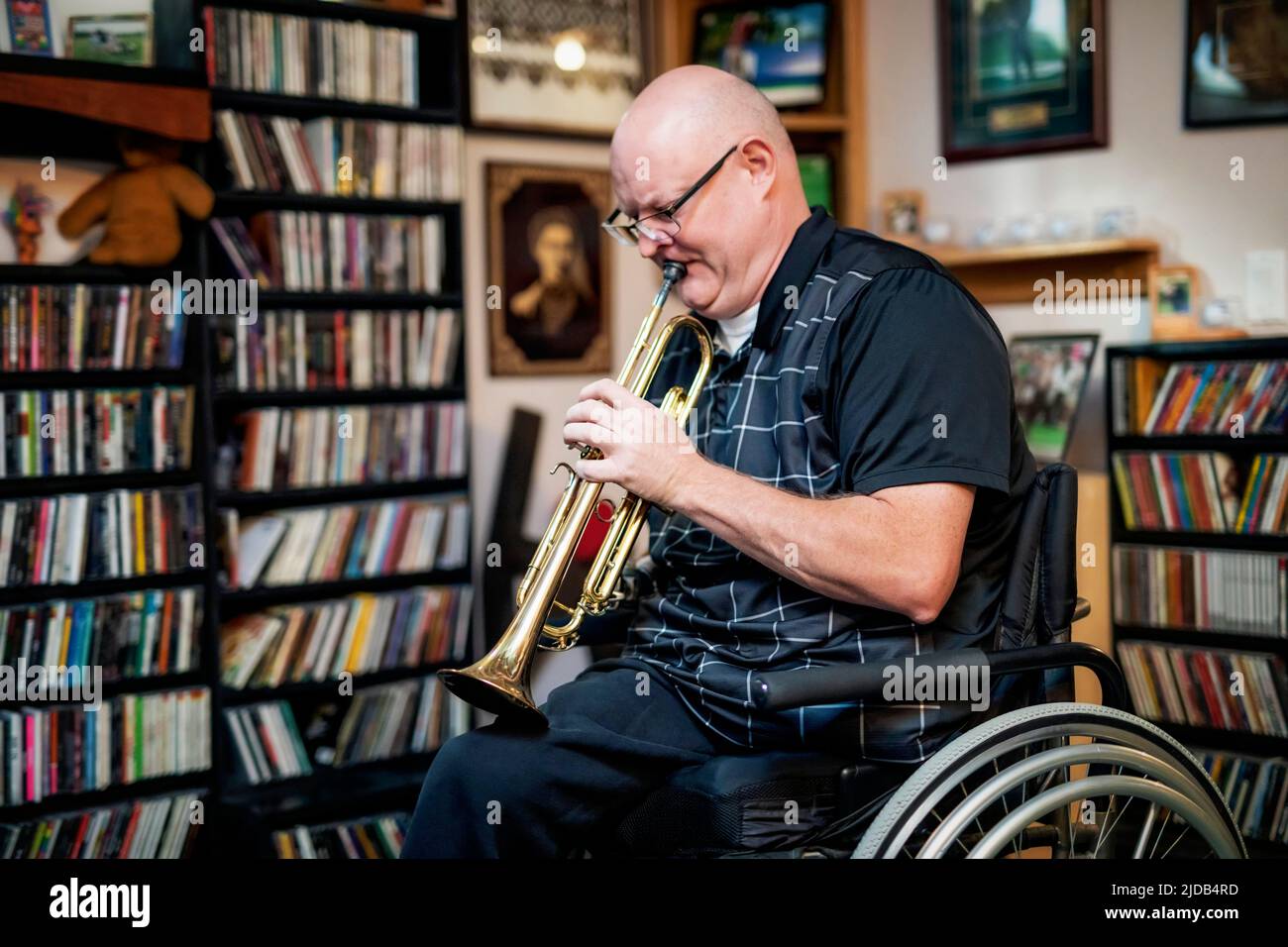 Man with double limb amputations playing the trumpet at home; St ...