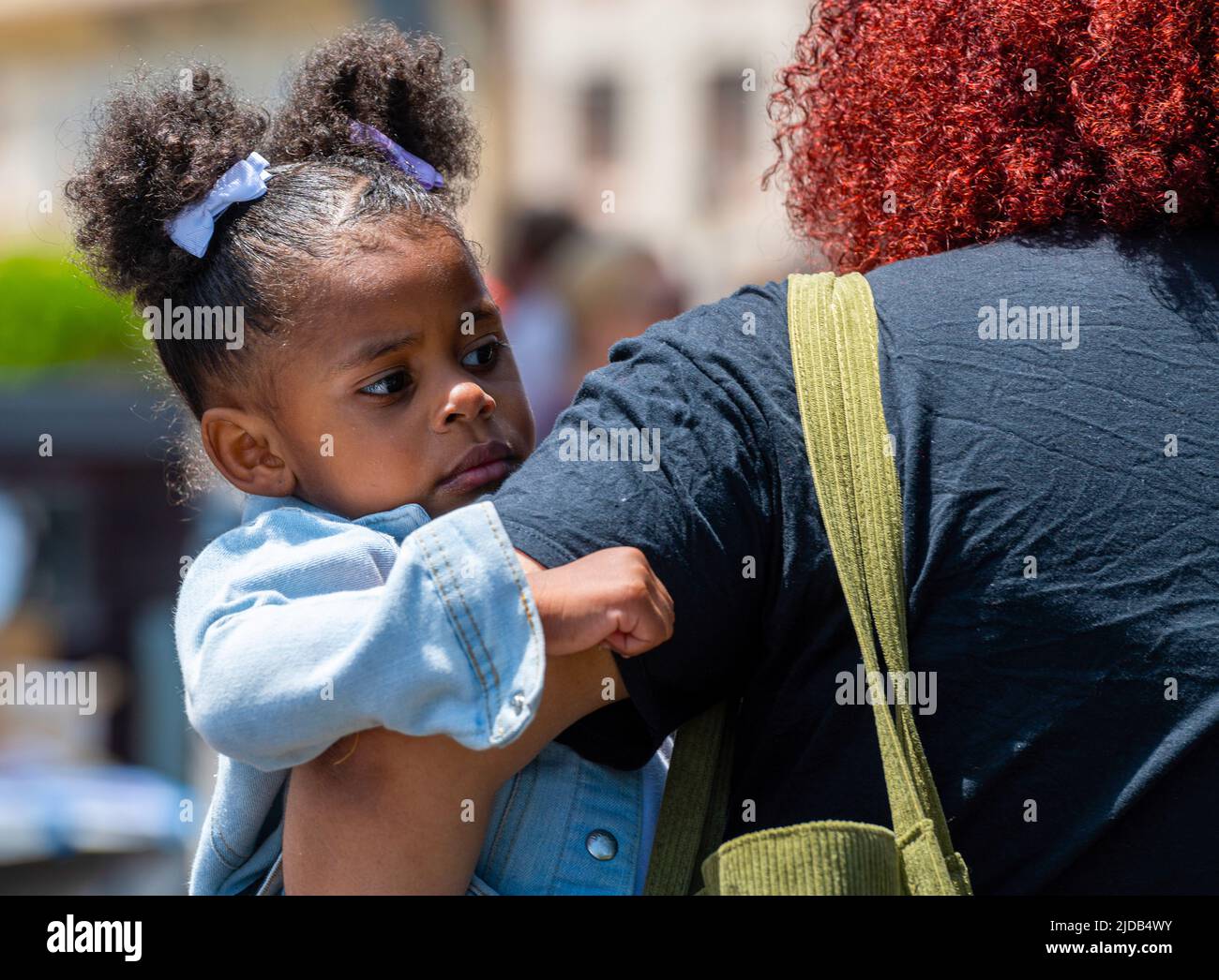 A baby peers over her mother's shoulder while they walk about a ...
