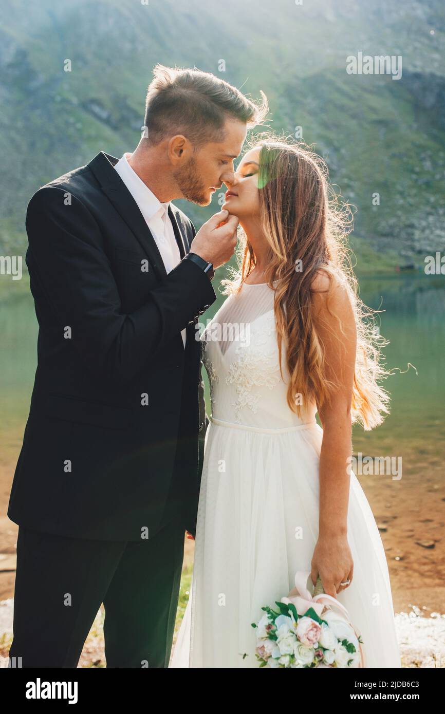 Romantic wedding couple in love standing by the lake at summer sunny ...