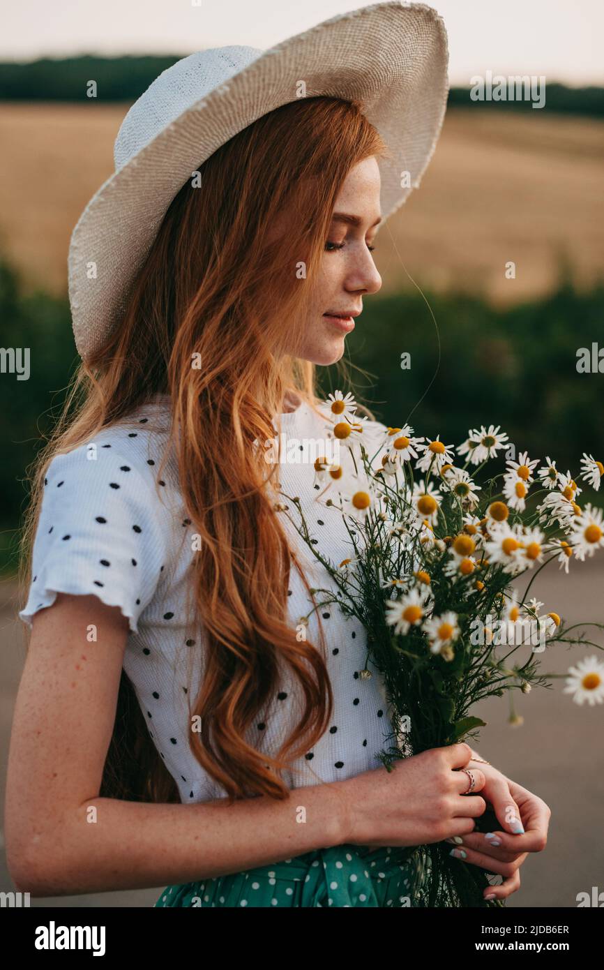 Elegant ginger model posing with bouquet of flowers at nature ...
