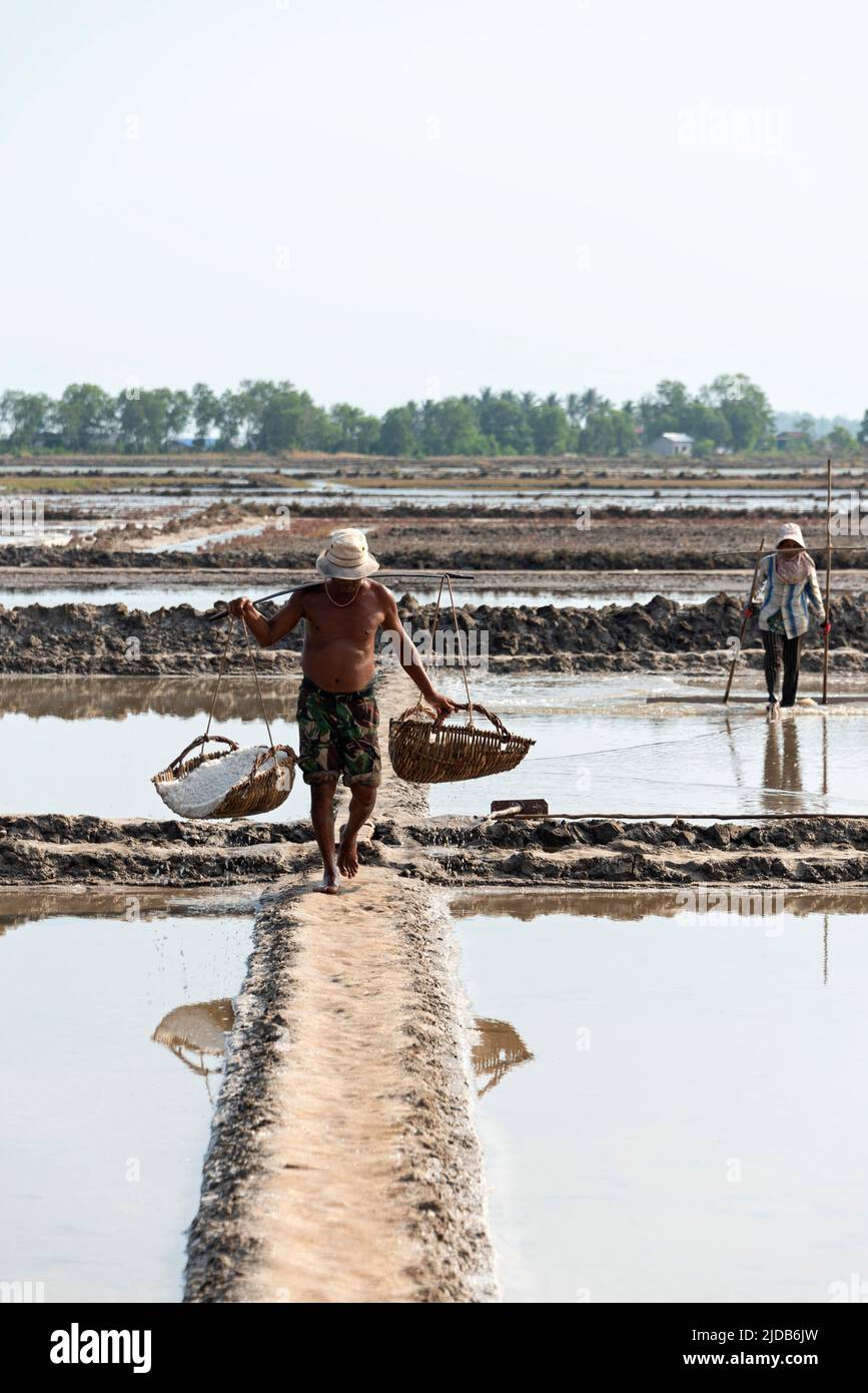 A man carries baskets of rice in a farming community in Southern ...