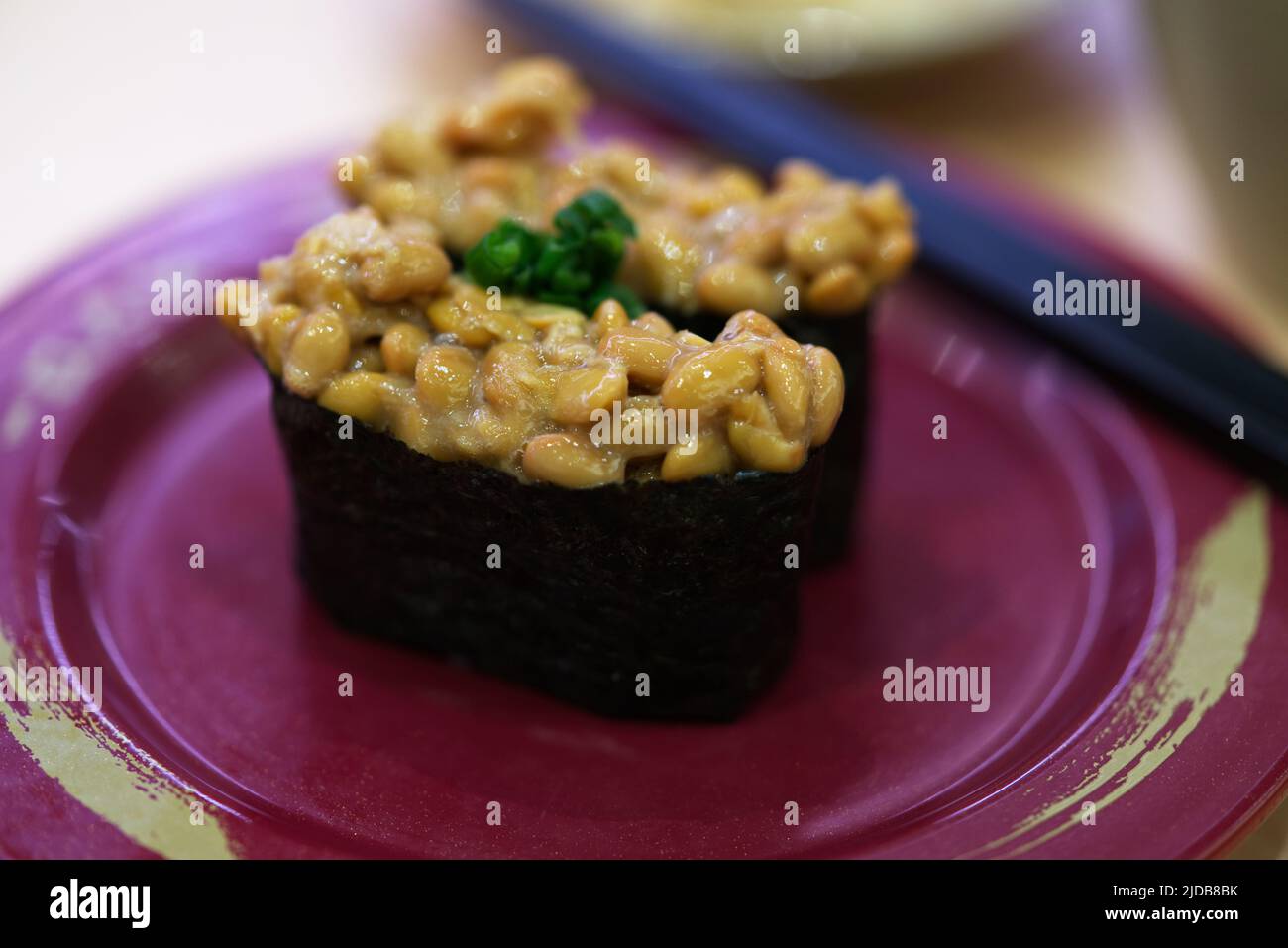 Natto or Fermented Soy sushi in a red dish on a table, topping with ...