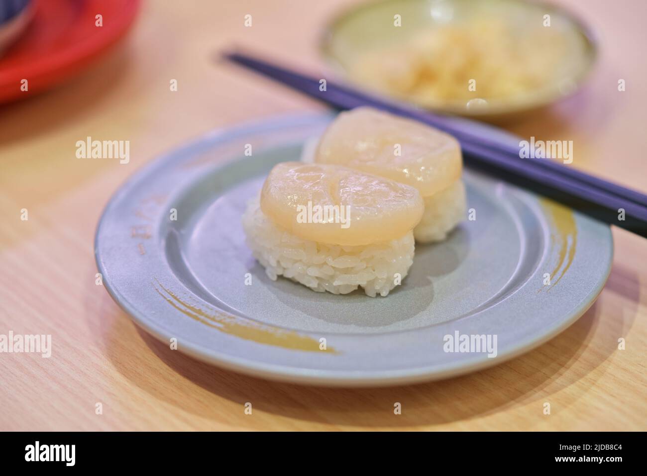 Close up raw scallop sushi in a dish on a restaurant table. Healthy ...