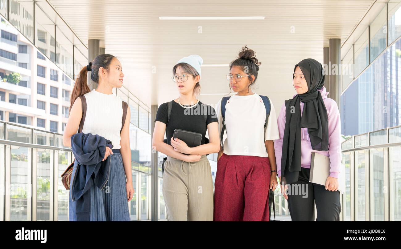 Group of multi-racial college student friends walking together in hall ...