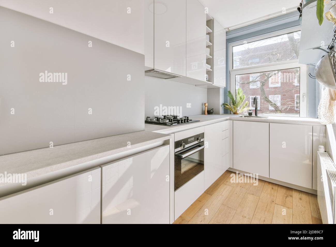 Light small home kitchen with wide window furnished with cupboards and ...