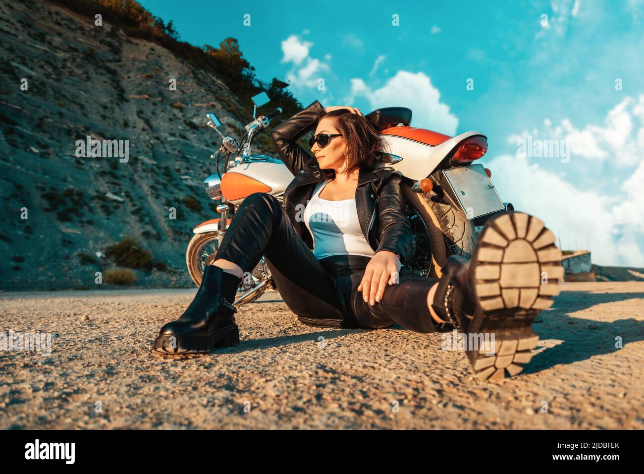 A cool independent woman in a leather motorcycle outfit poses sitting ...