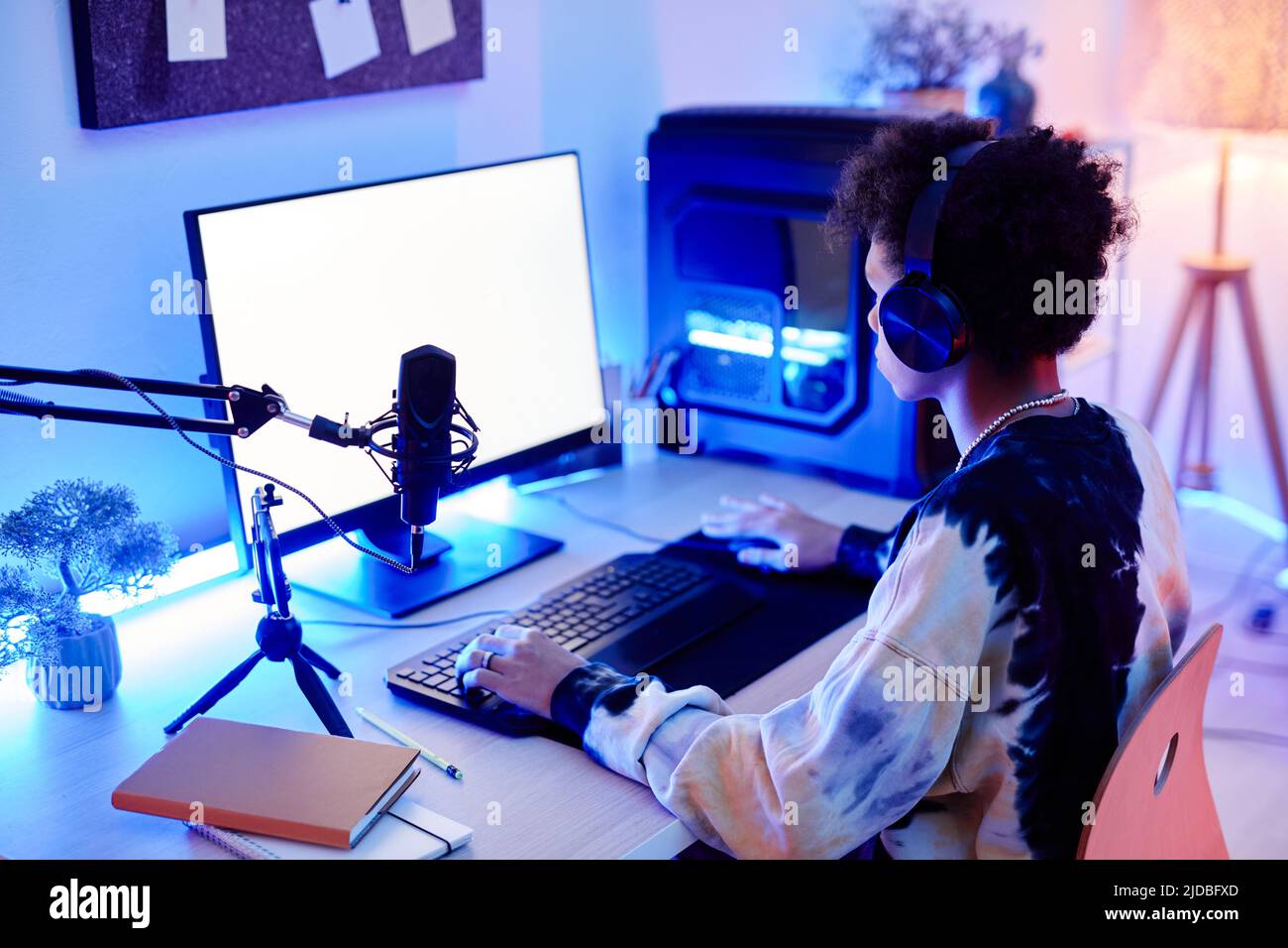 Side view of teenage boy playing video game on PC and streaming live in ...