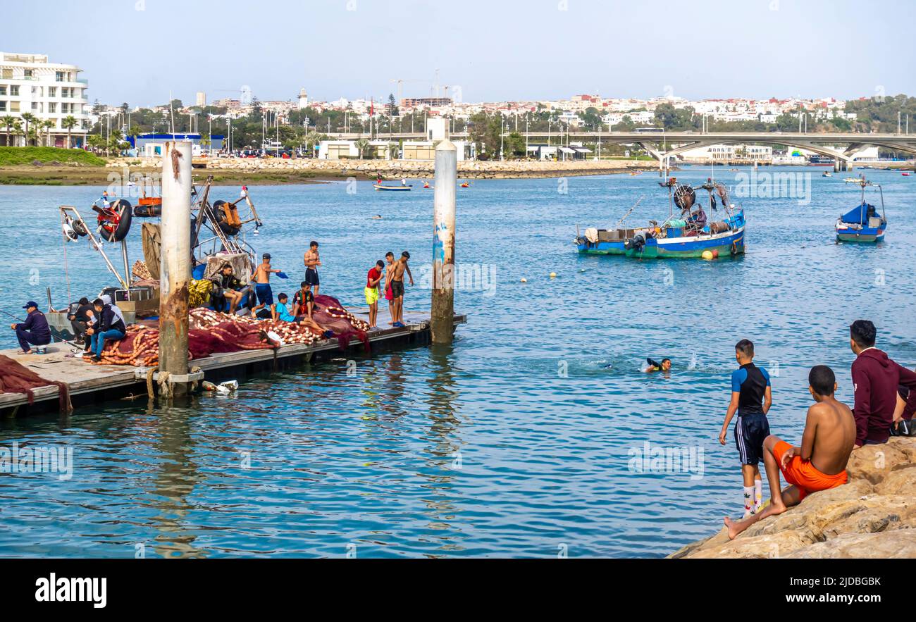 Kids swimming at the bay pier with fishing boats and nets in central ...