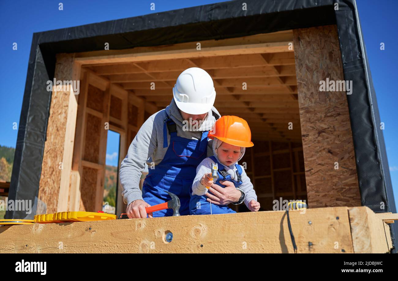Father with toddler son building wooden frame house. Male builders ...