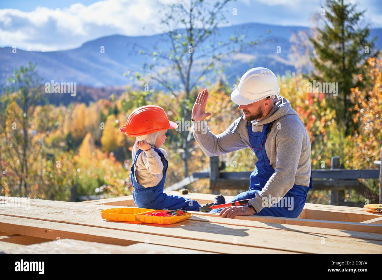 Father with toddler son building wooden frame house. Male builder ...