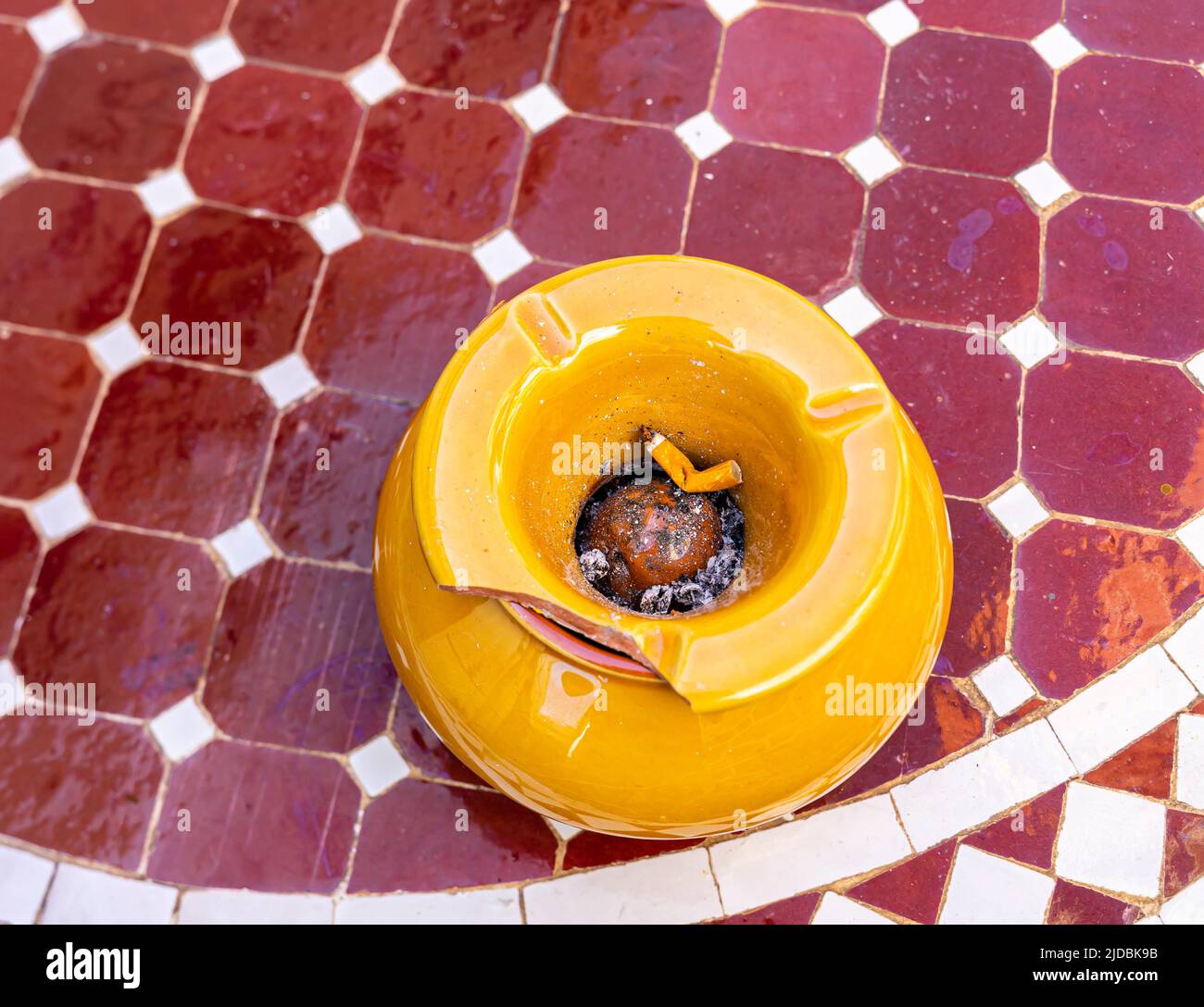 Yellow Arabic ashtray on dark red table - Moroccan home features Stock ...