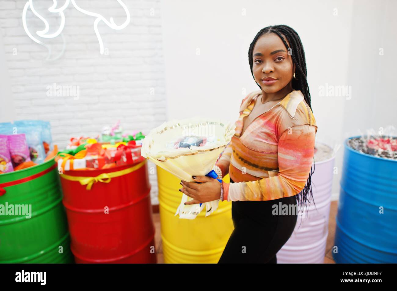 African american millennial lady at candy shop with bouquet of sweets ...