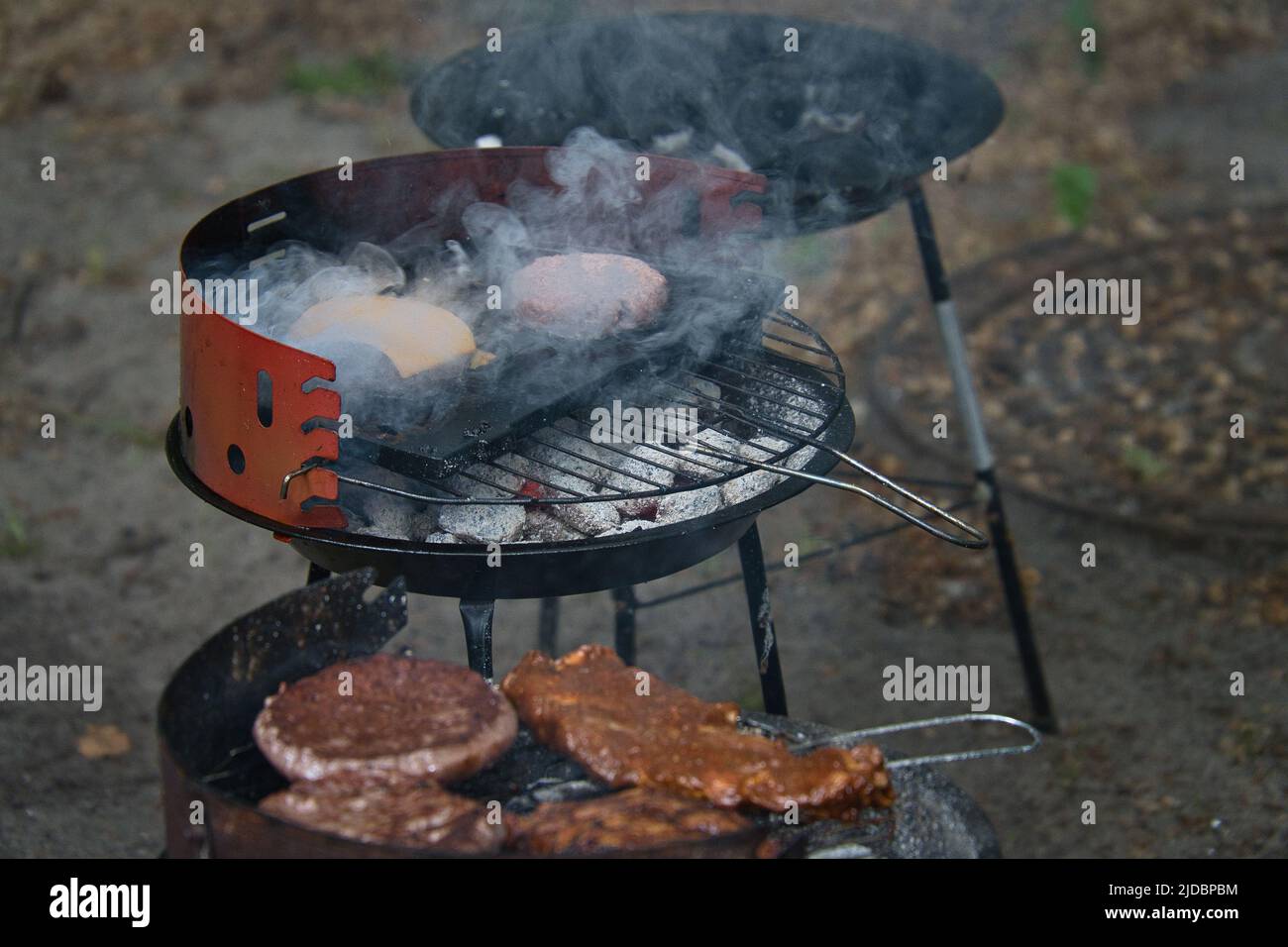 Grill with coal, grate and meat. Burger with cheese in the preparation ...
