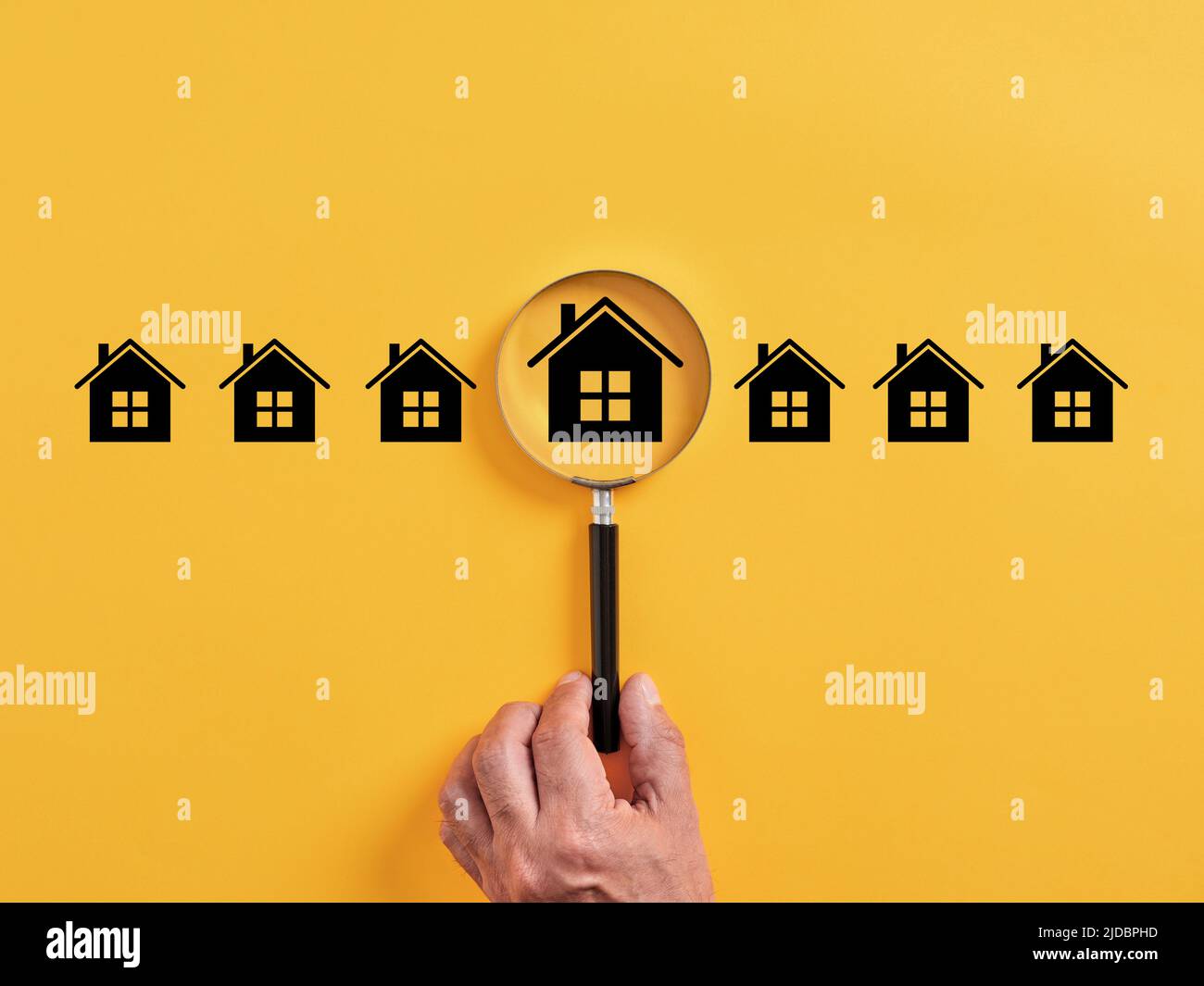 Male hand holds a magnifier focusing on a house symbol. Searching for a ...
