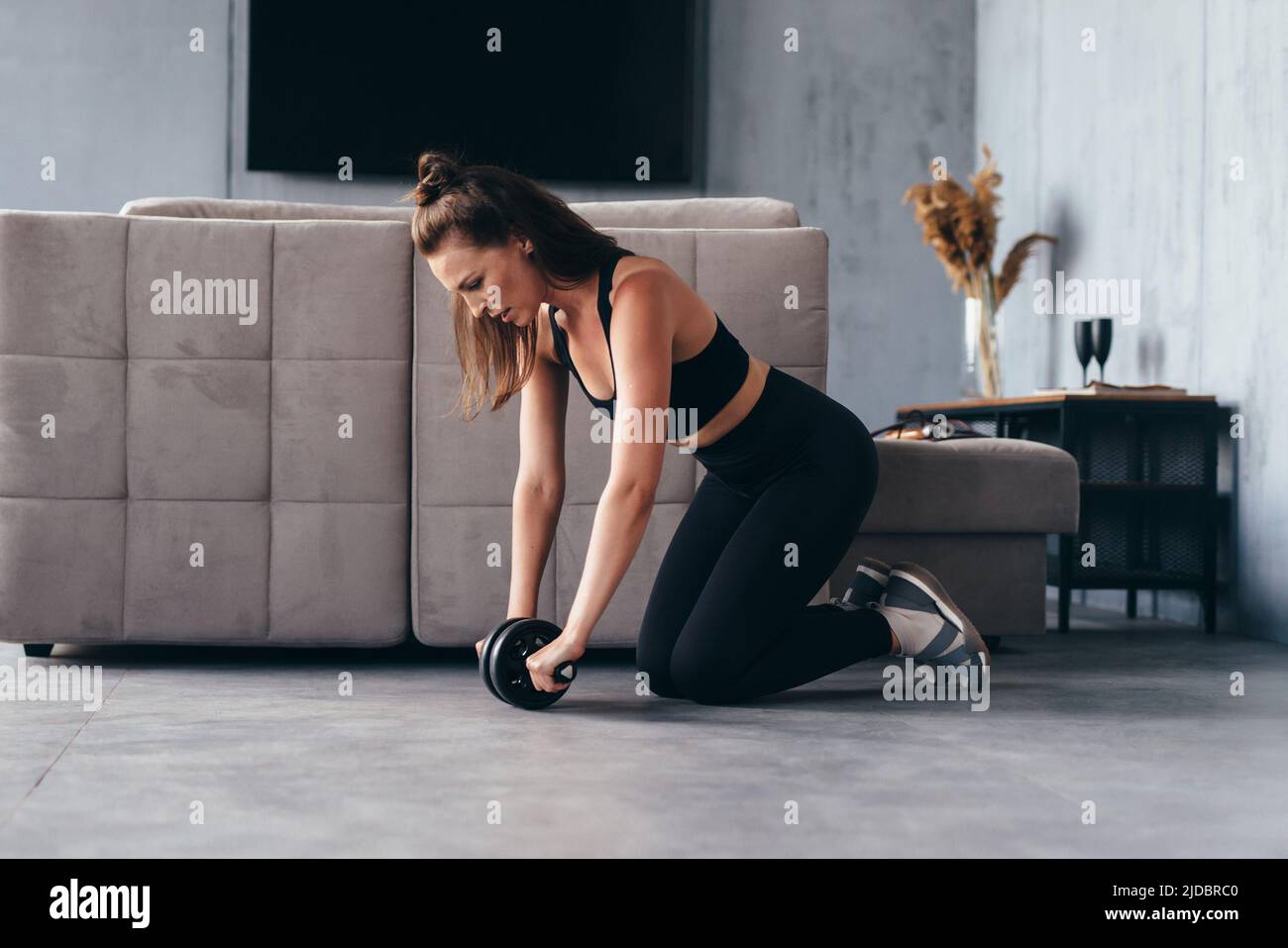 Fit woman working out with ab exercise wheel at home Stock Photo - Alamy