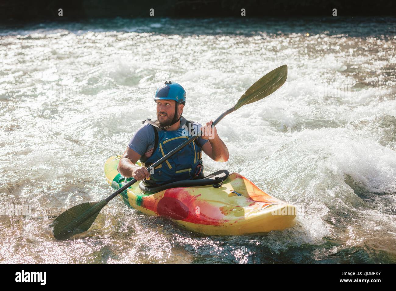 Caucasian man kayaking over the mountain river rapids, with the ...