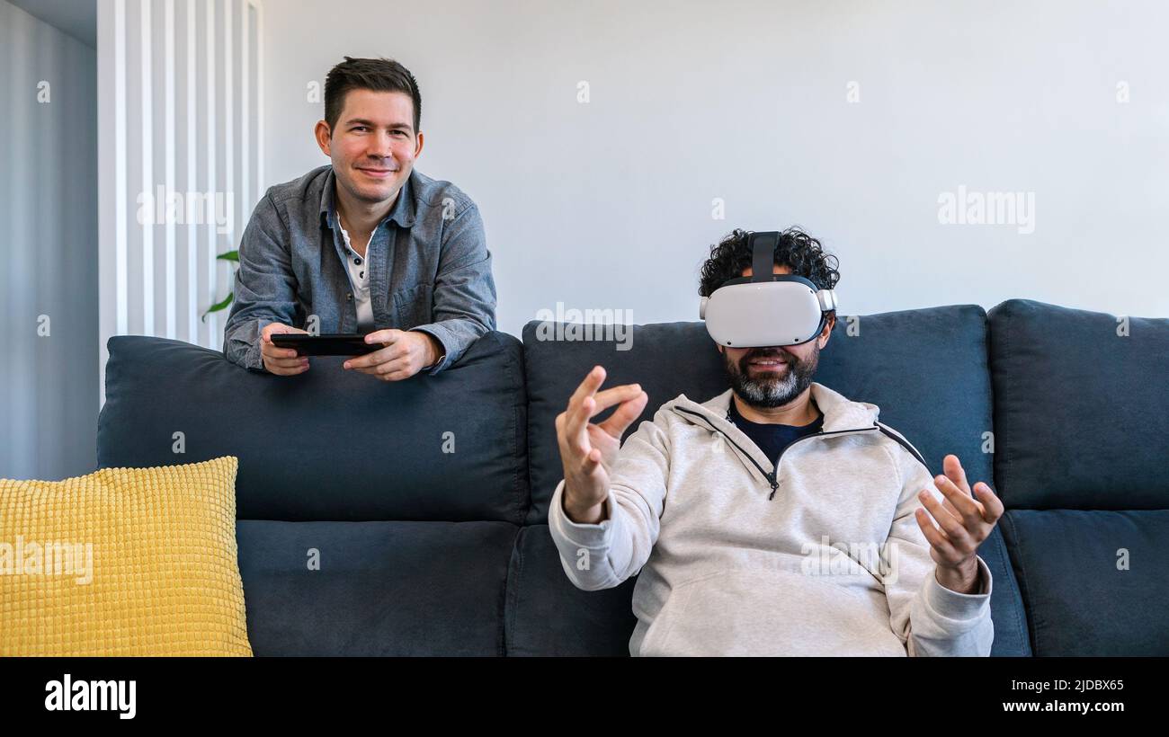 Roommates are sitting on sofa in living room and watching 360 virtual ...