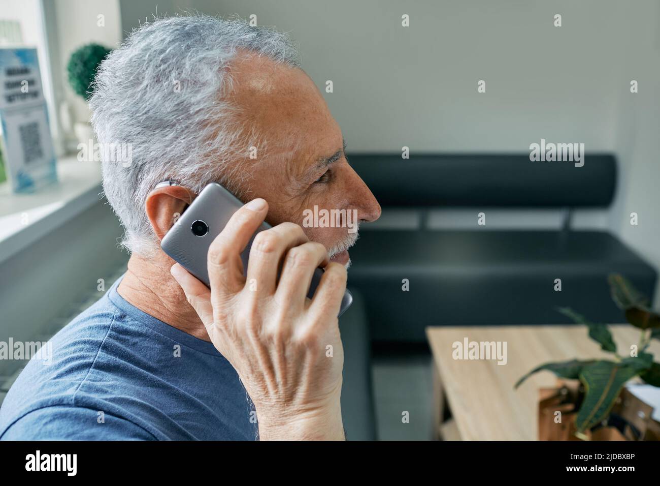 Using your hearing aids with a smartphone . Senior man with hearing aid ...