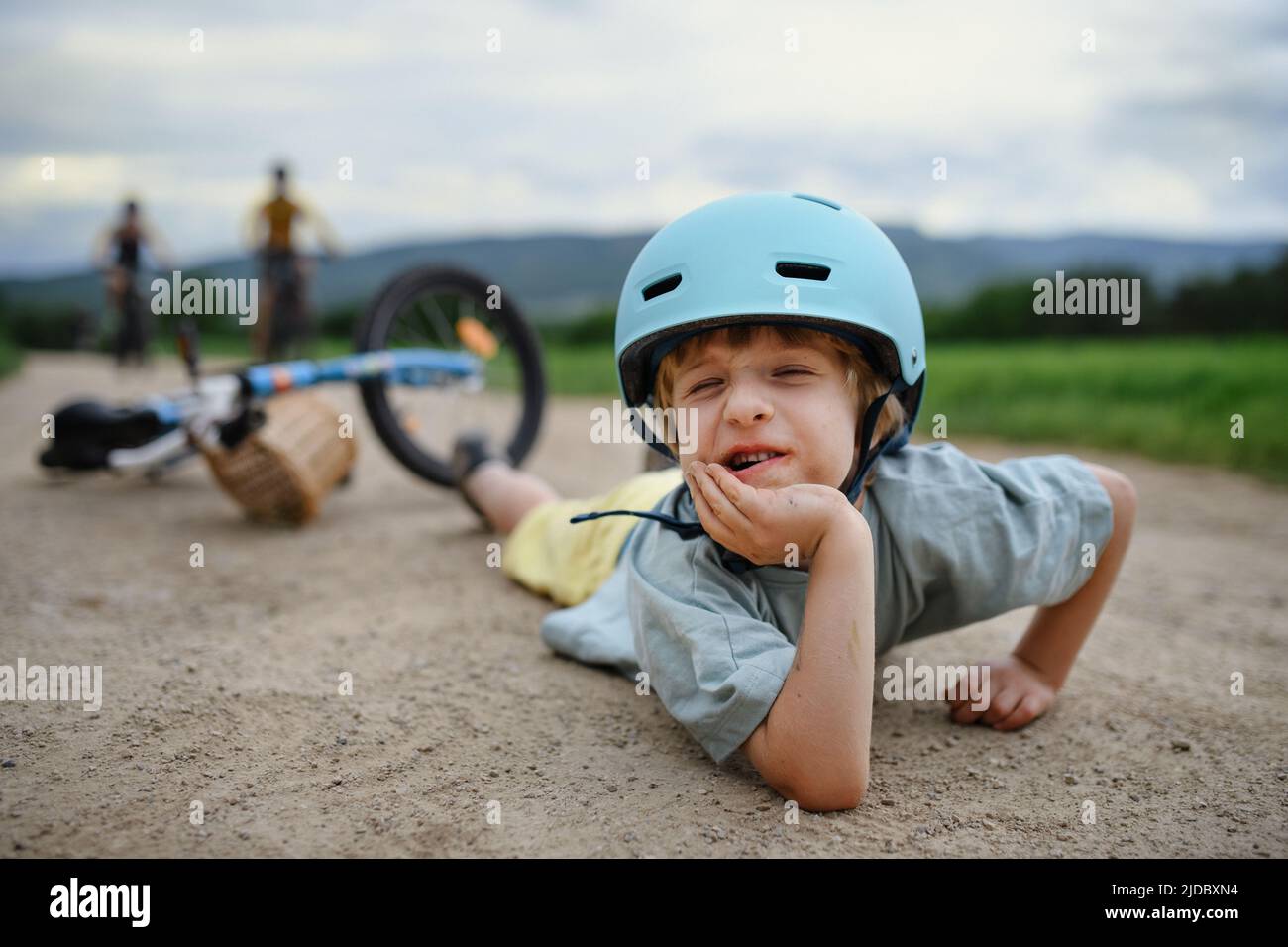 Little boy fell off his bike and lying on path and crying, with his ...
