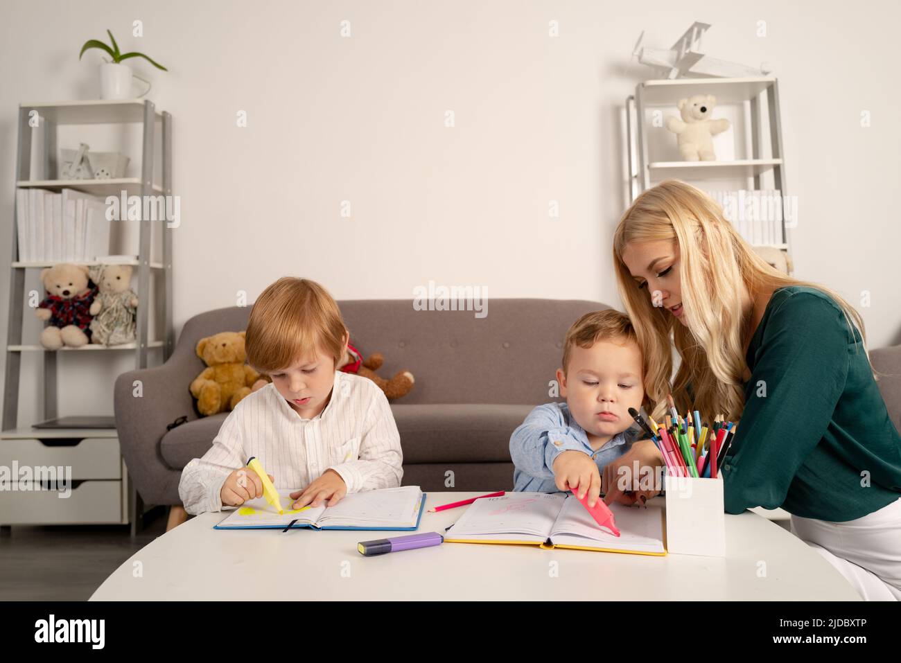 Mother and two son together draw, paint. Mom helps the children boys ...